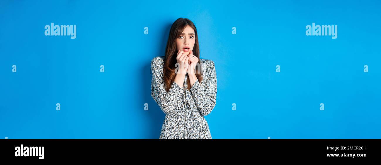 Scared and timid woman in dress, shaking from fear, gasping with hands ...