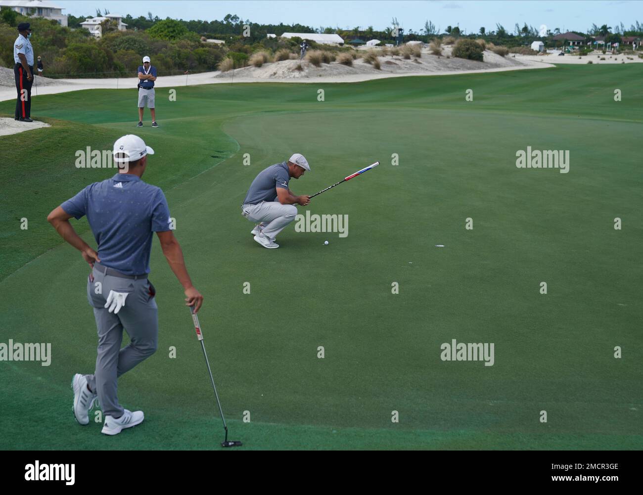 Bryson DeChambeau, of the United States, center, lines up his putt on ...