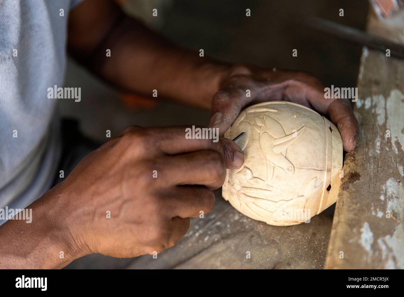 Local artisan carving traditional images on a cup from a coconut in a ...