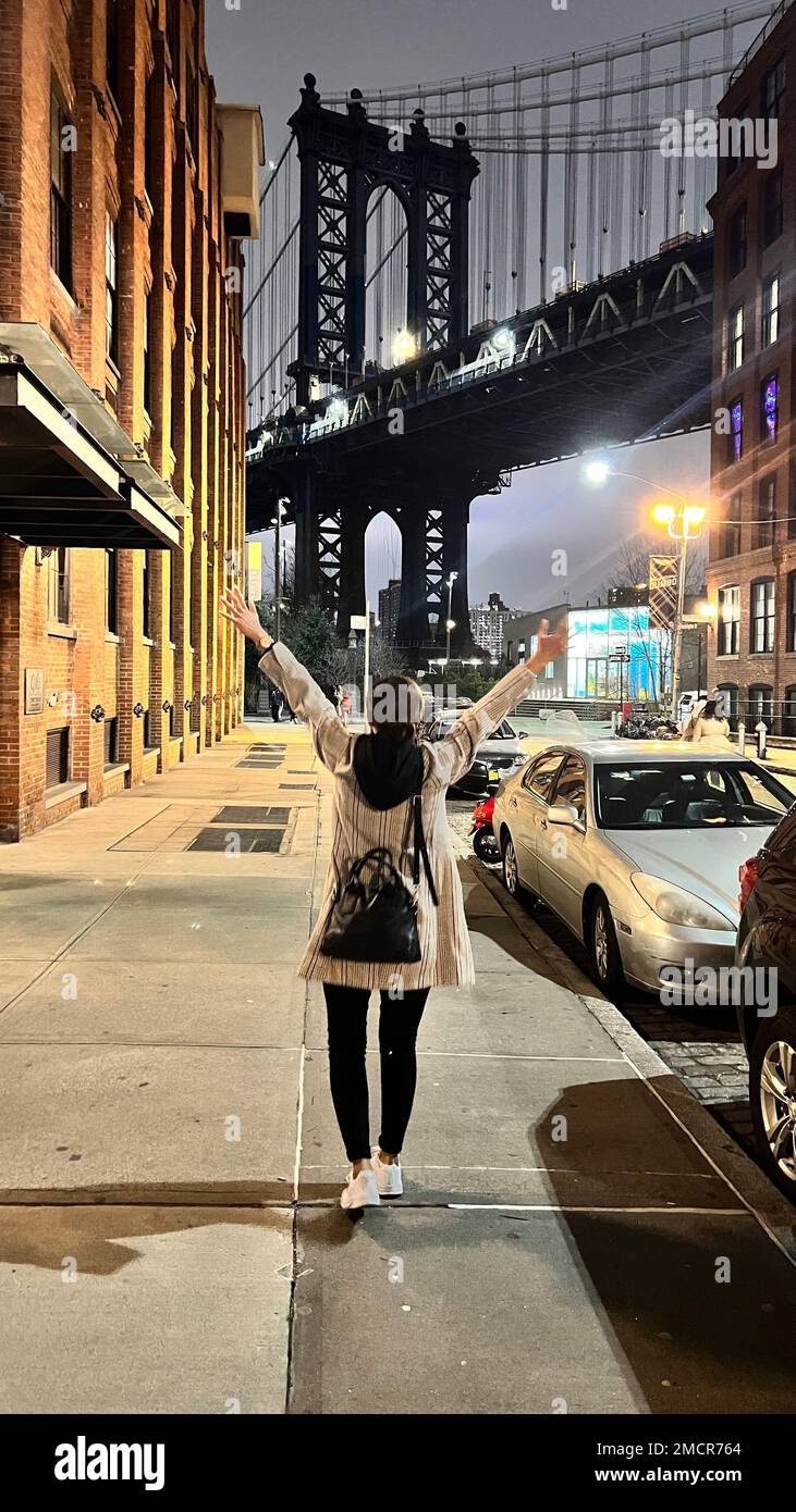 A tourist admiring the Manhattan Bridge View at night from Dumbo view ...