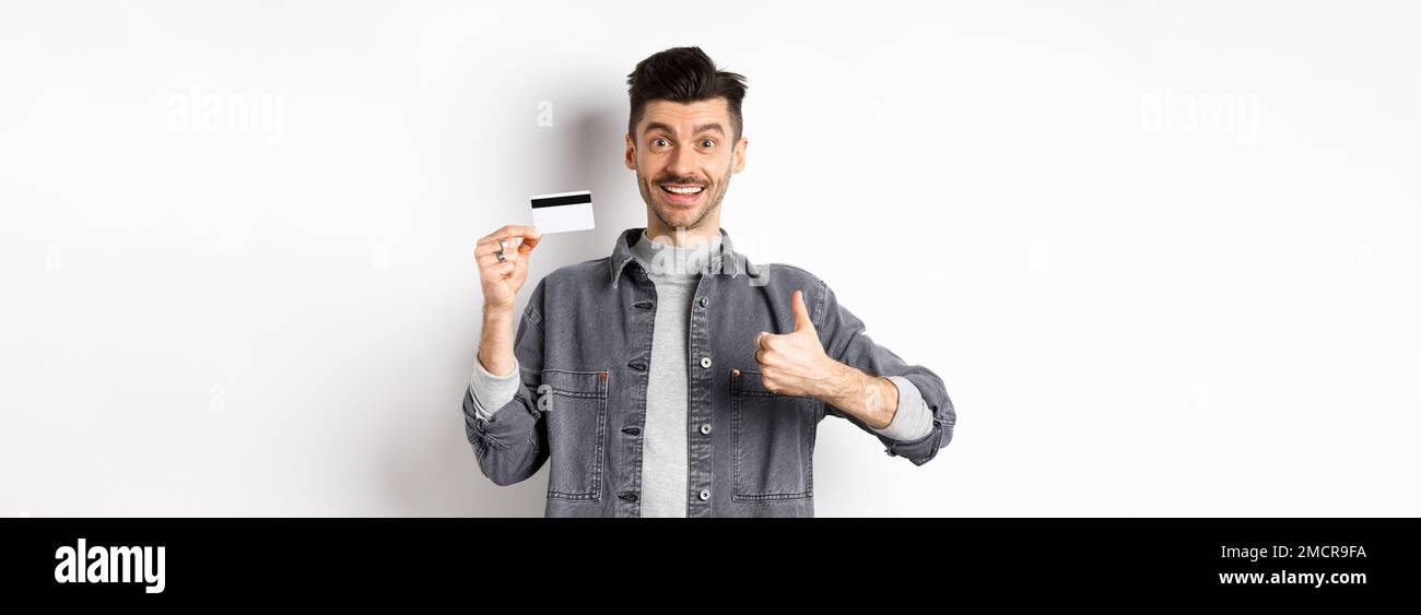 Very good. Smiling guy with plastic credit card showing thumbs up ...