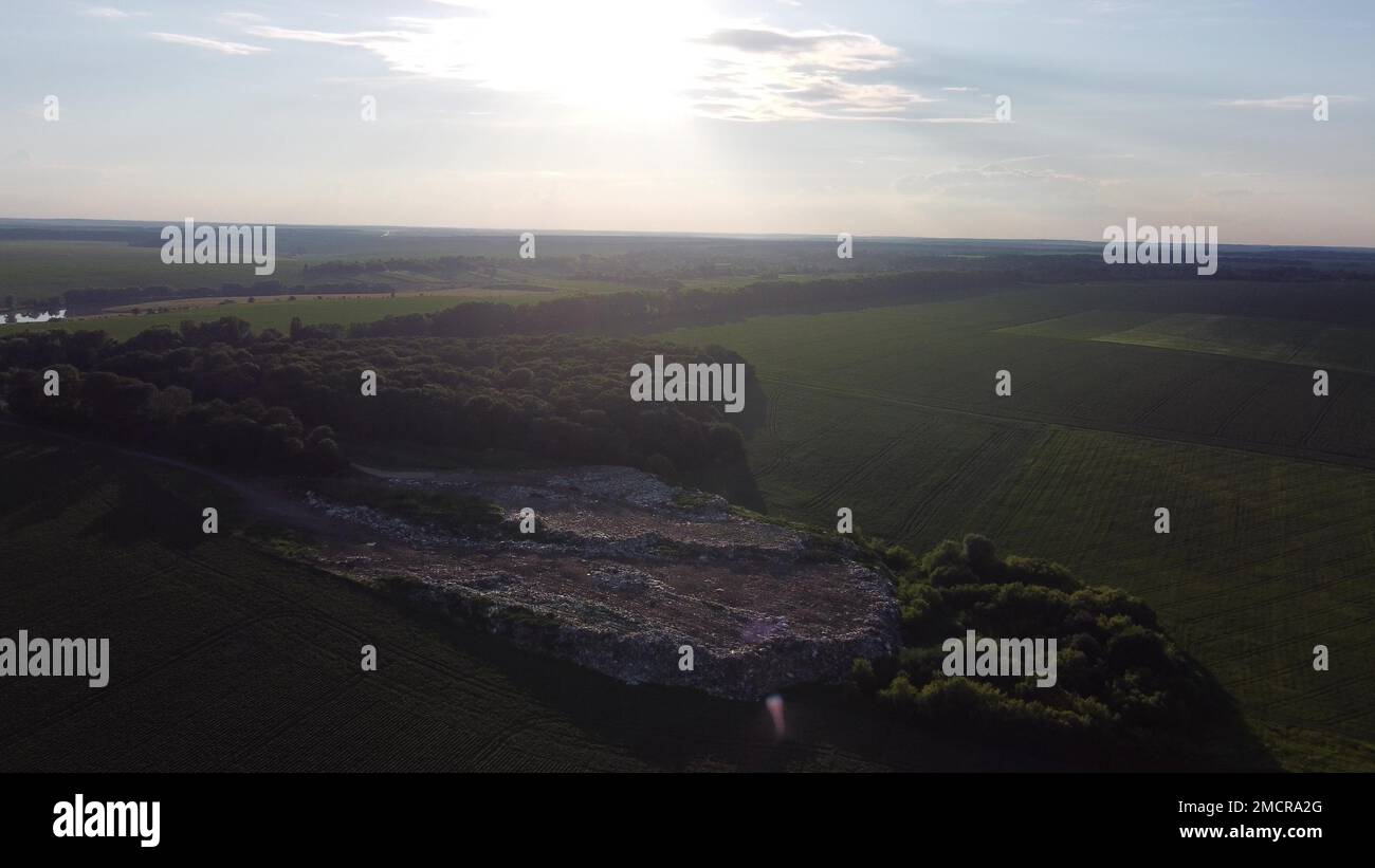 Aerial shot of big rubbish pile lying among field in countryside ...