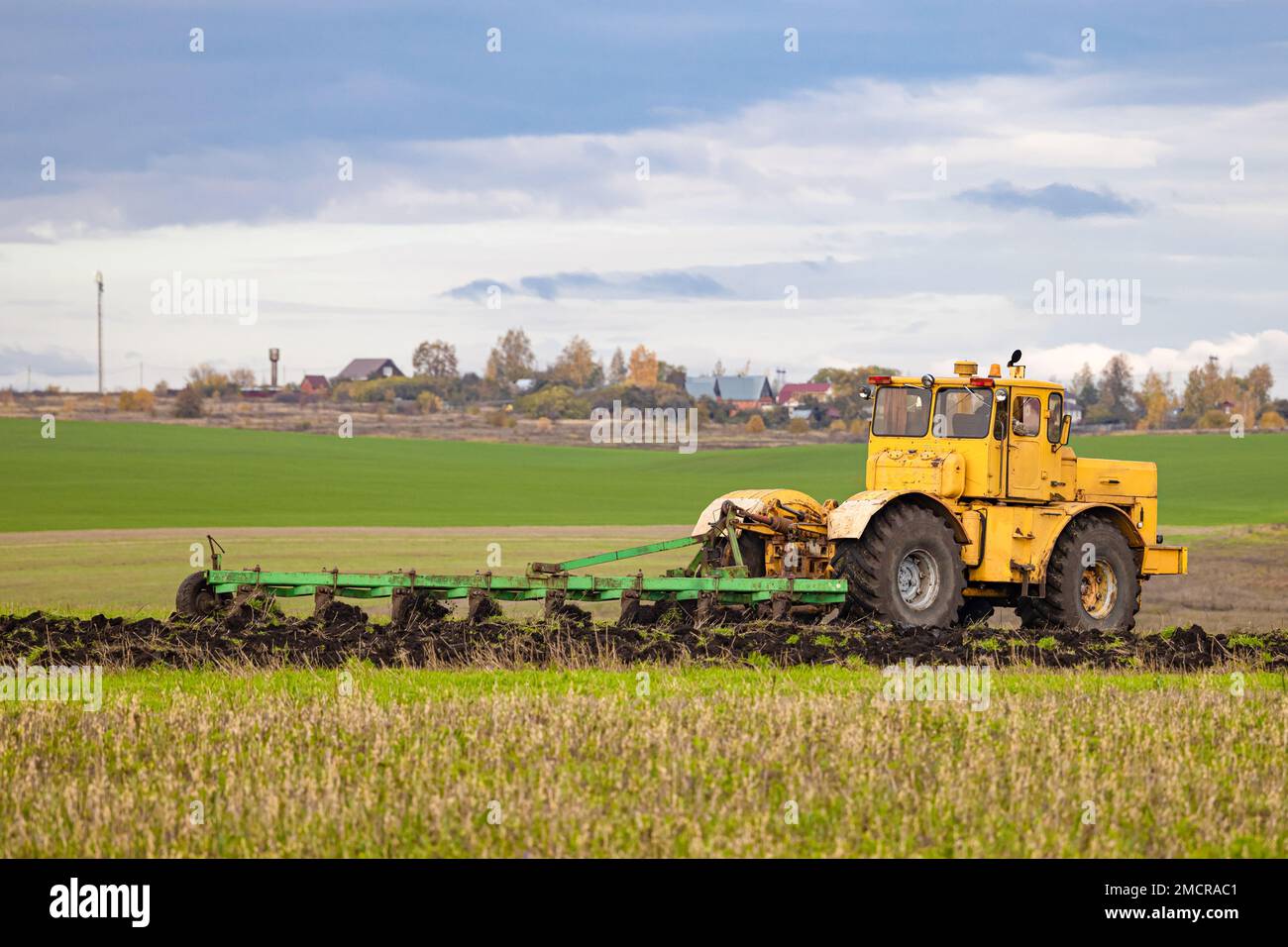 tractor plows the field for sowing in spring. old tractor plows the ...