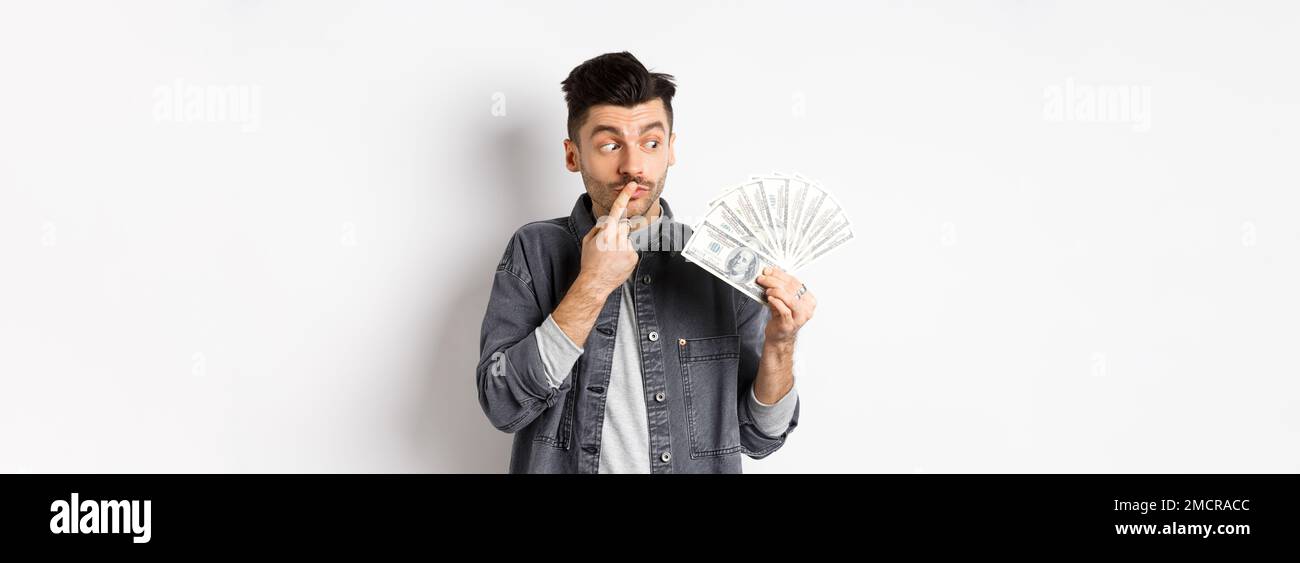 Man thinking of shopping while looking at dollar bills, holding money ...