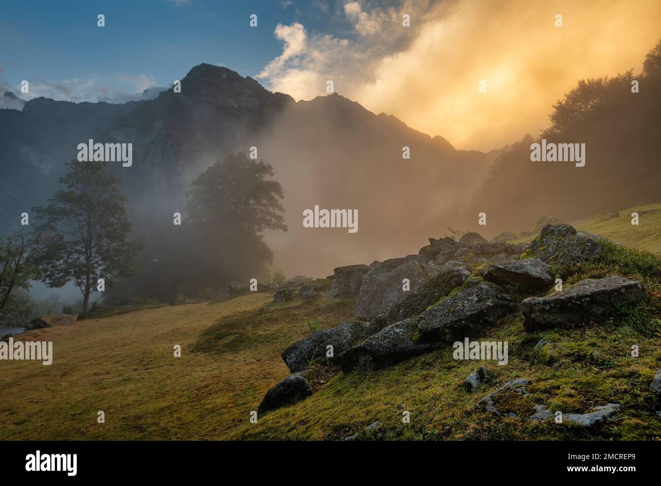 A sunset between the mountains with deep clouds and warm light Stock ...