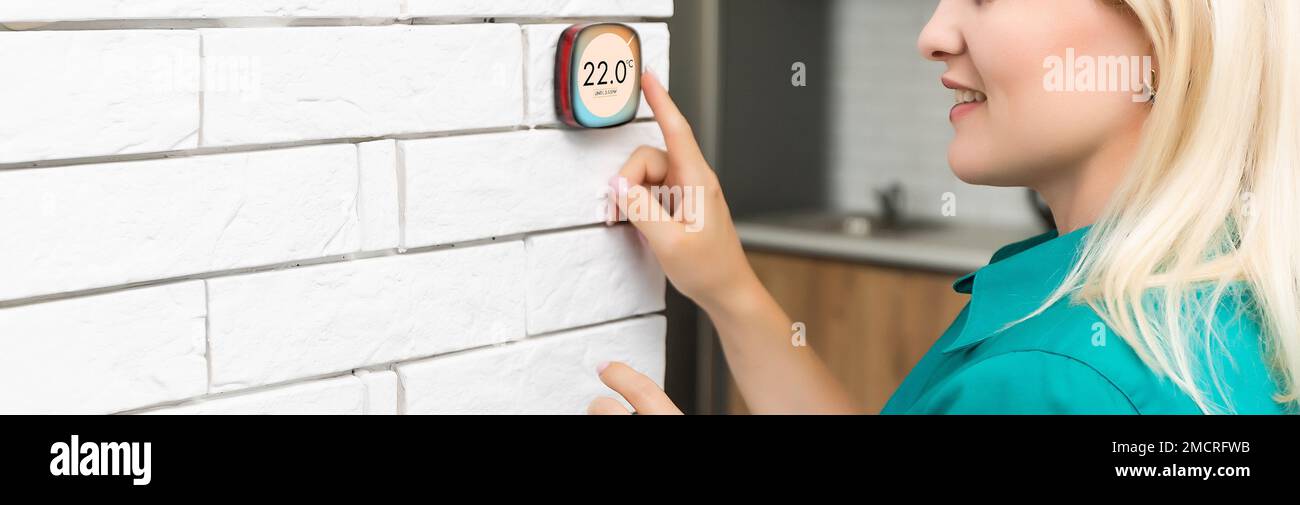 woman regulating heating temperature with a modern wireless thermostat ...