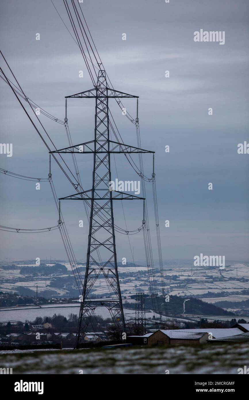 Pylons on a freezing cold winters morning with snow on the farmland and ...