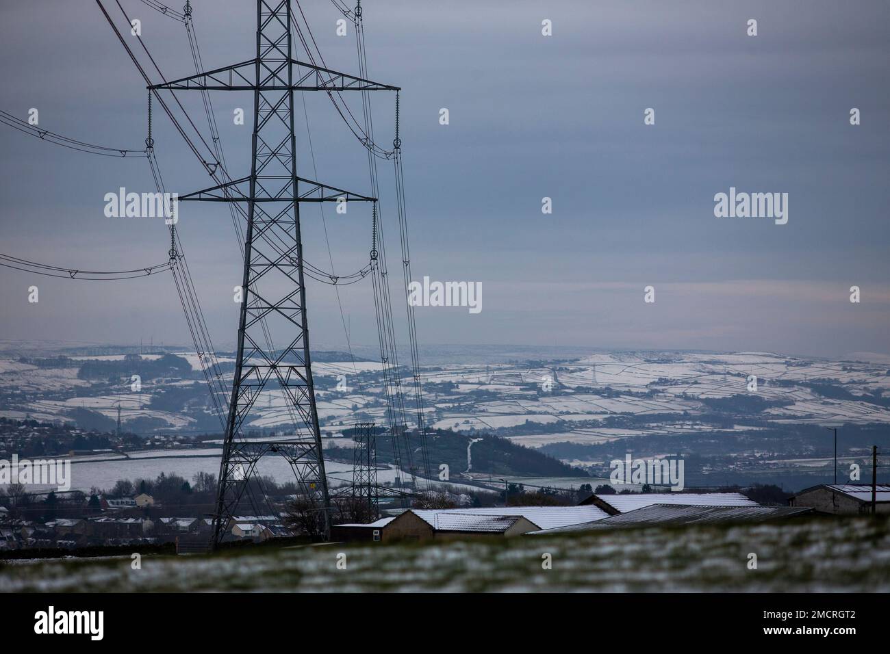 Pylons on a freezing cold winters morning with snow on the farmland and ...