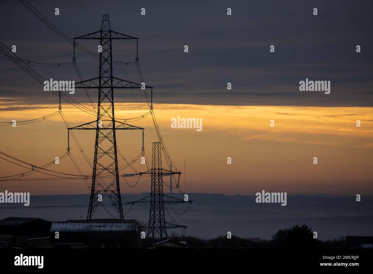 Electricity pylons cross frozen farmland as the sunrises over the snowy ...
