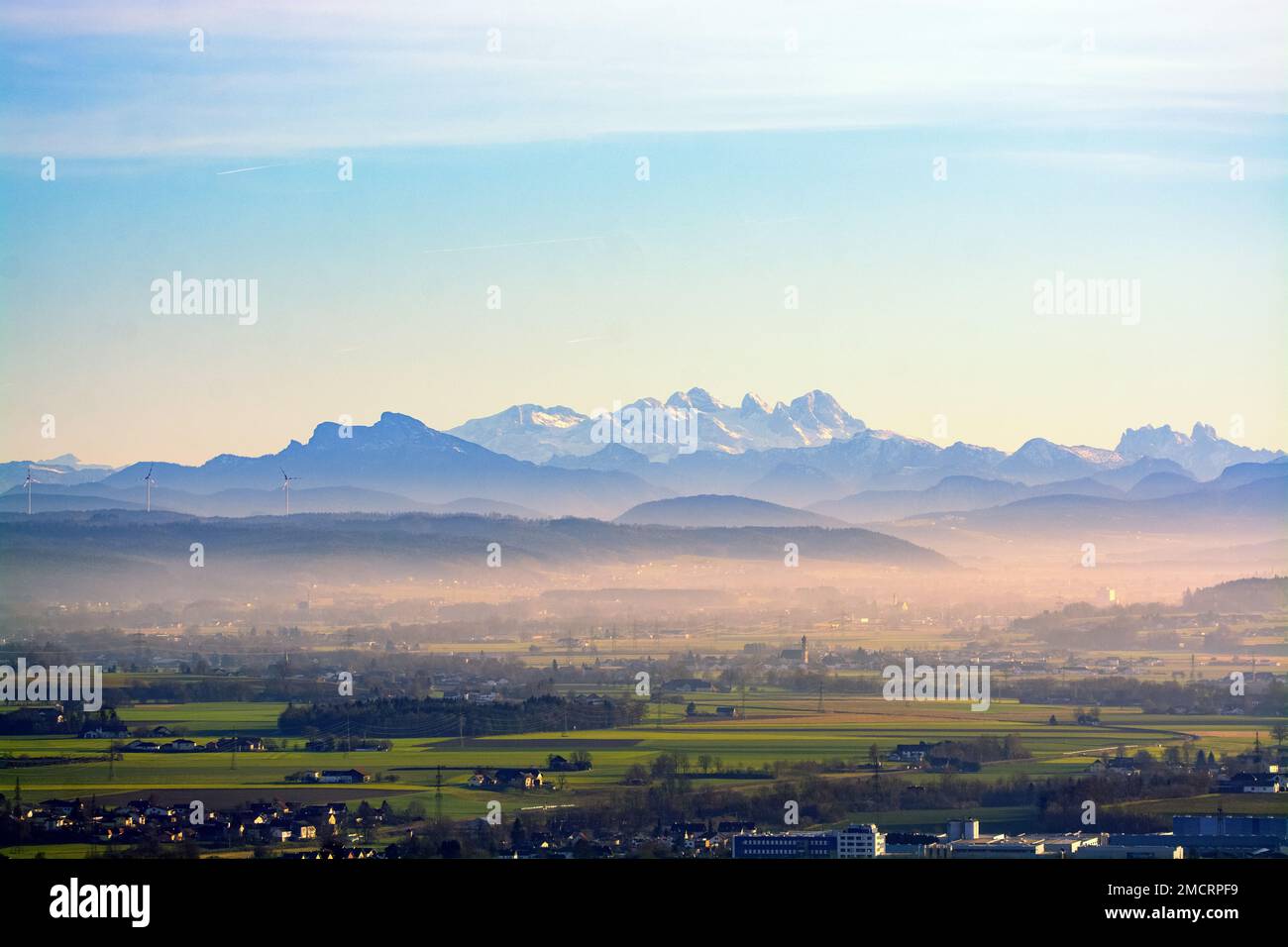 A landscape scene of meadows and rural houses with hazy mountains on ...