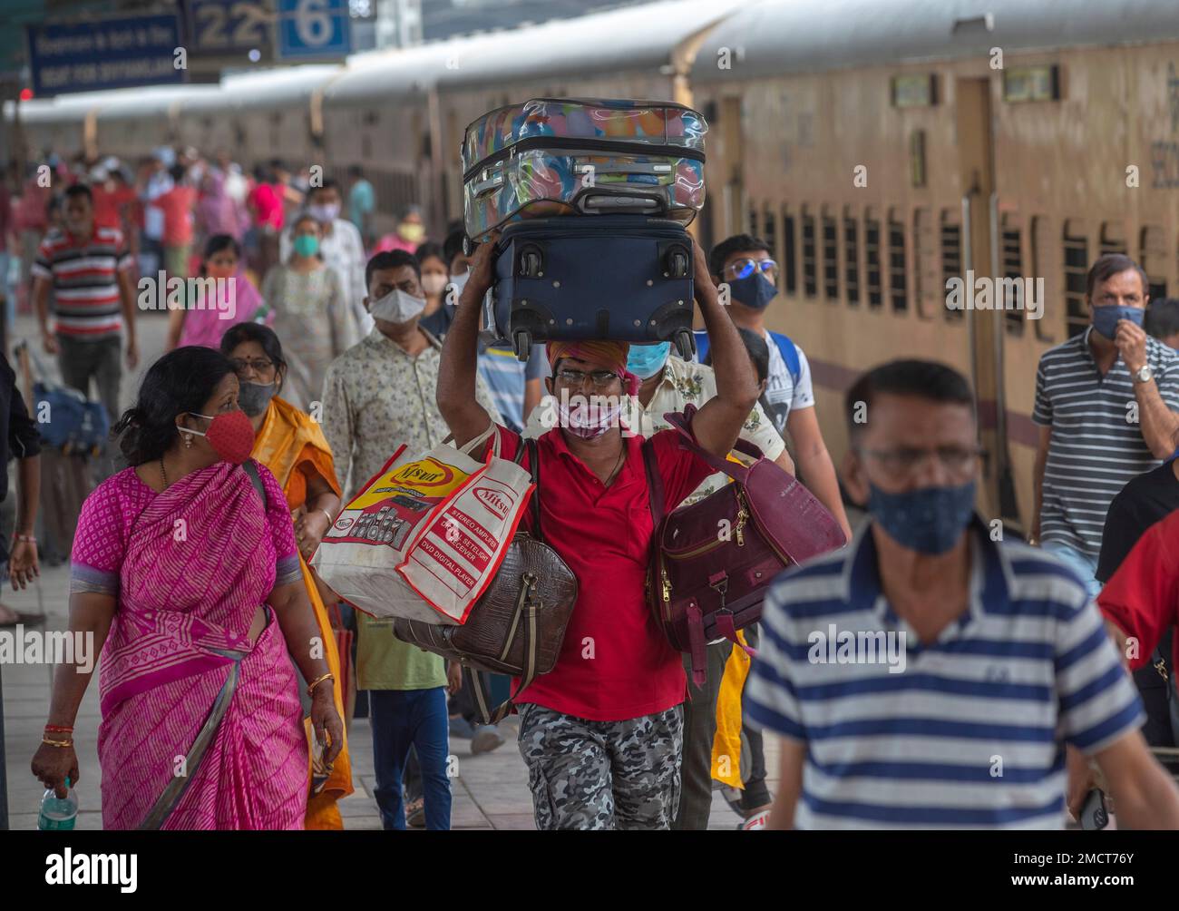 A porter carries luggage as people wear masks as a precaution against ...