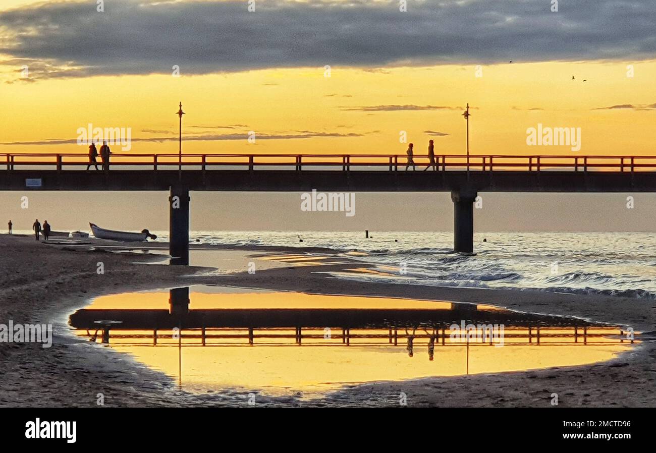 A bridge on the background of the sunset reflecting on the puddle water ...