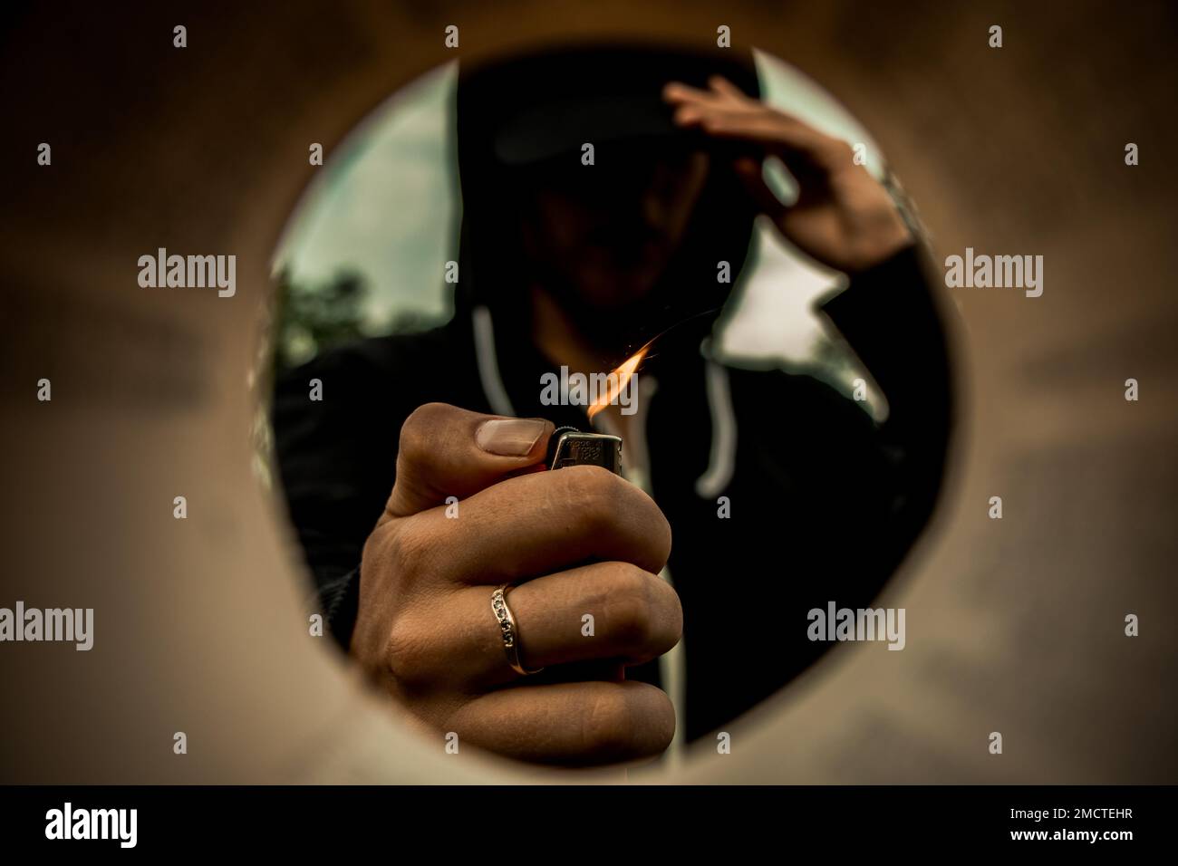 A mysterious man holding a flaming gas lighter in his hand with a ring ...