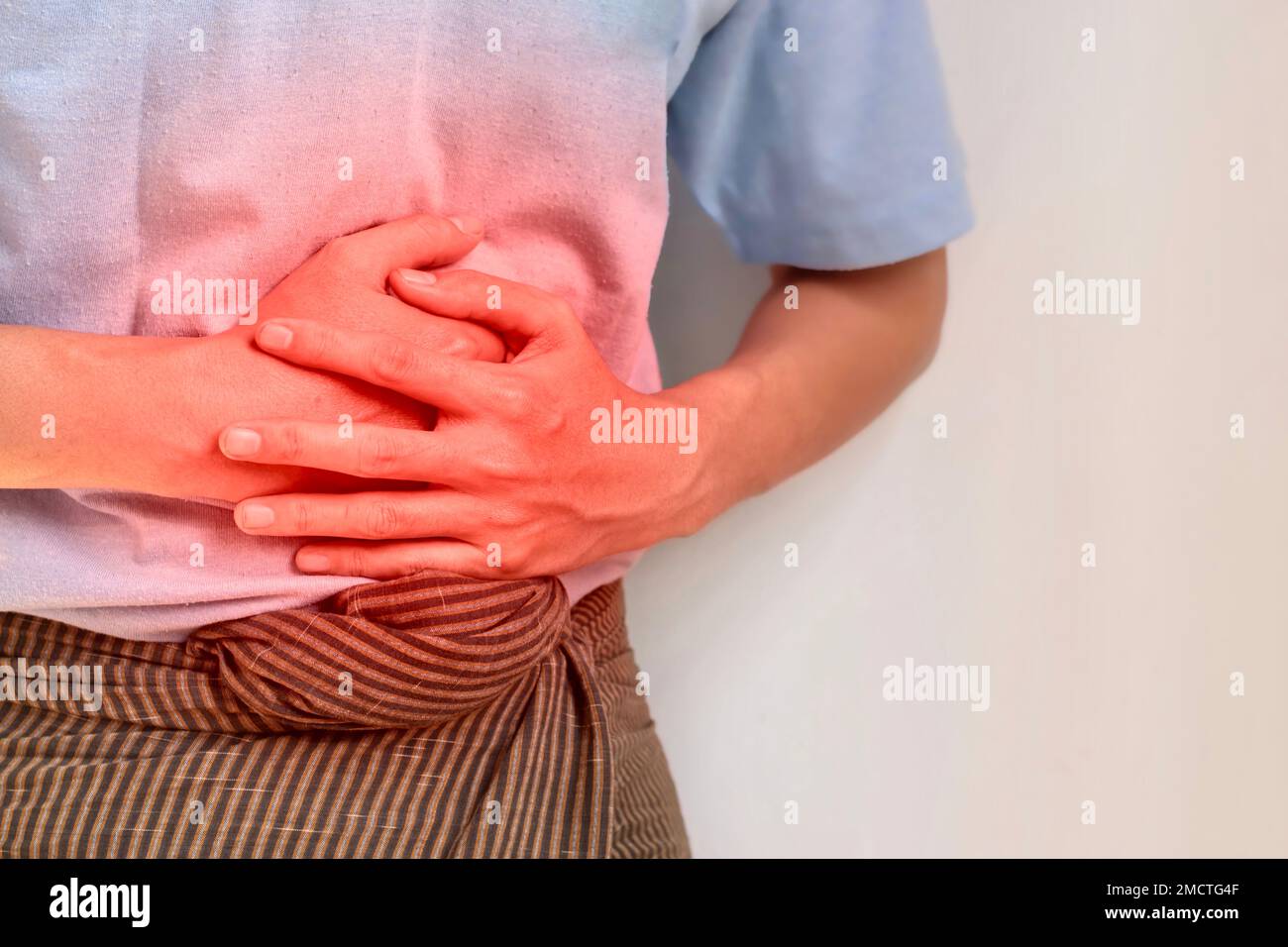 Asian young man suffering from upper abdominal pain. It can be caused ...