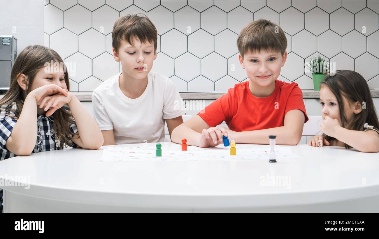 Portrait of group of excited children friends sitting at white table in ...