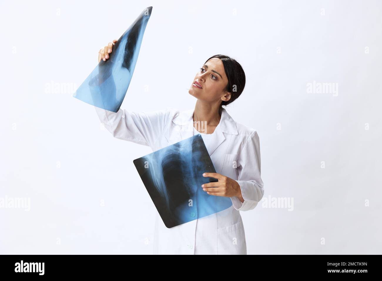 Woman doctor holding X-ray in robe on white background, consequences of ...