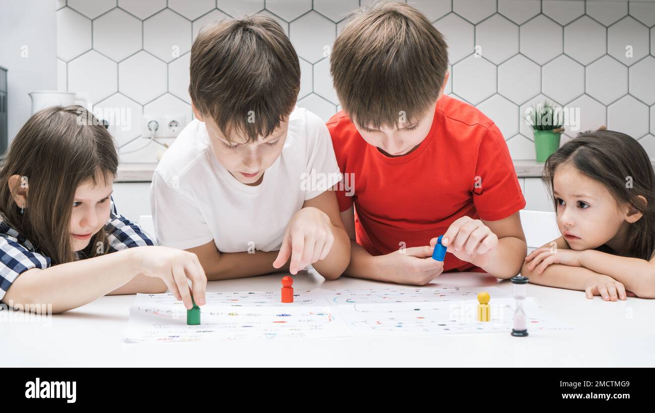 Portrait of group of busy children friends sitting at white table in ...