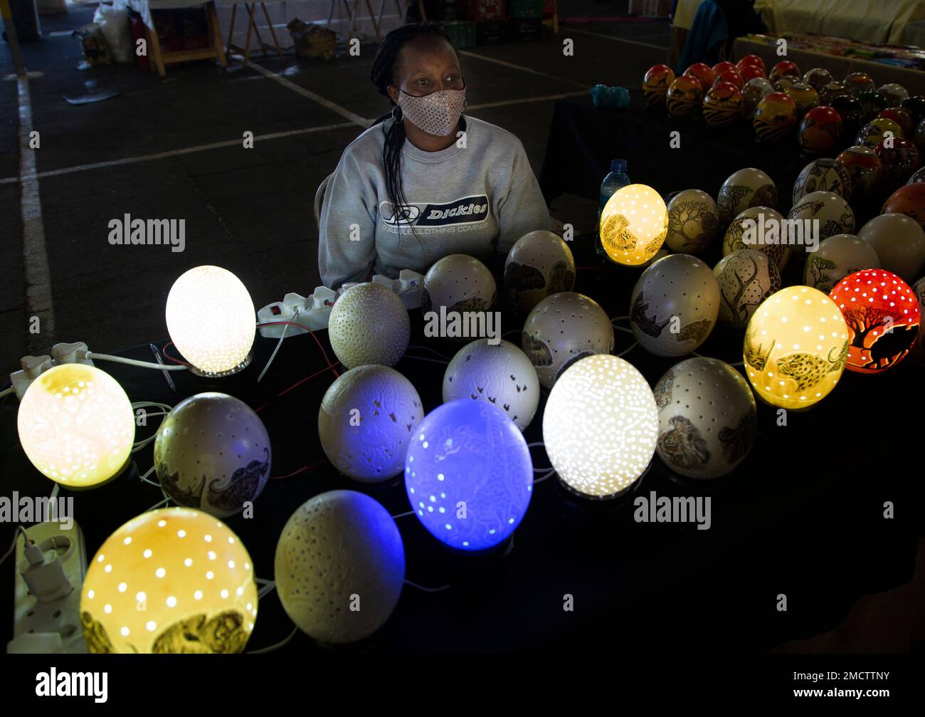 A stall-holder at Rosebank Mall Rooftop Market sits behind ostrich egg ...