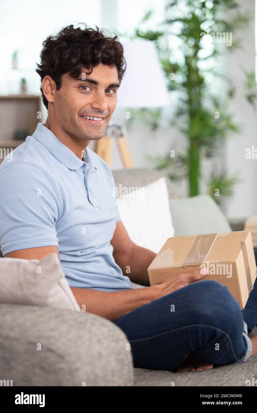 man sits legs crossed on sofa holding cardboard box Stock Photo - Alamy