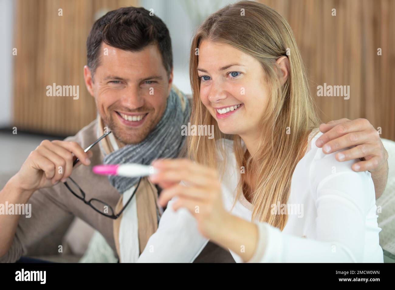 happy young woman holding pregnancy test sitting besides husband Stock ...