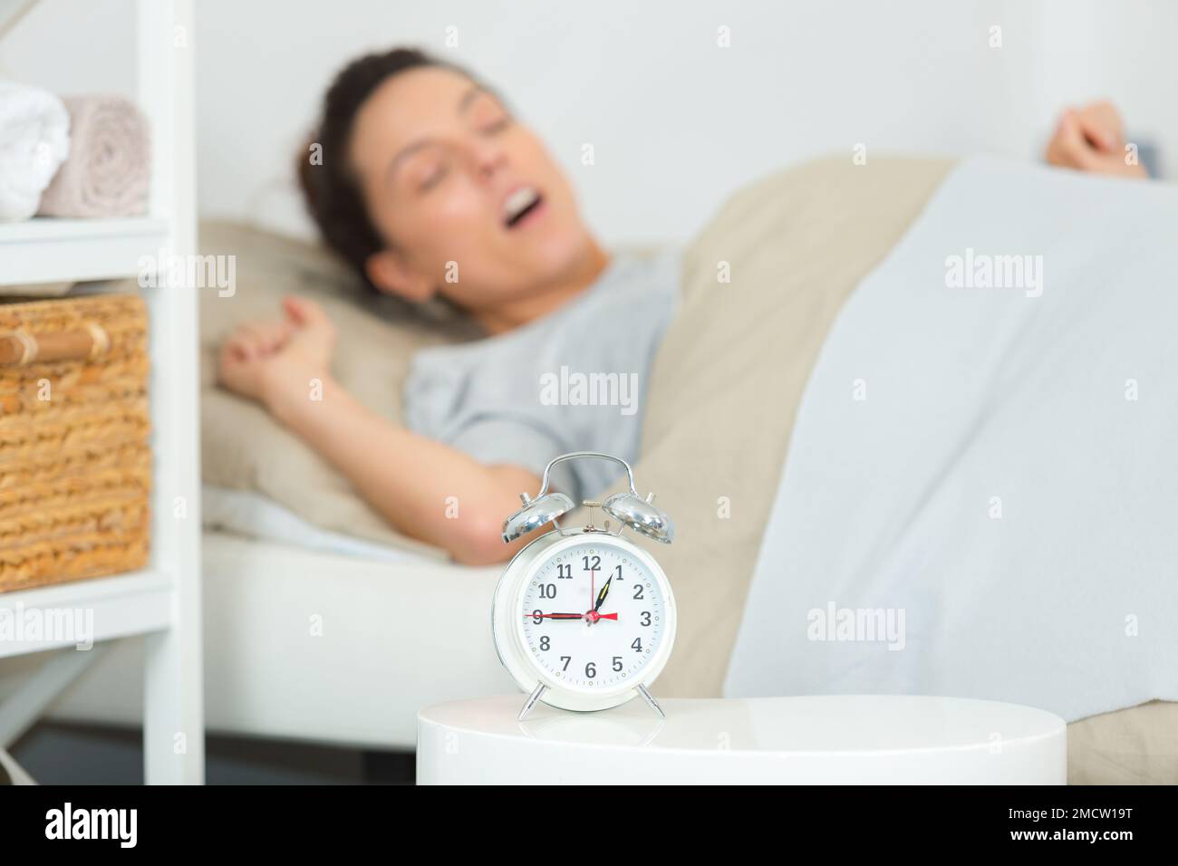 sleepy young woman stretching to turn alarm off Stock Photo - Alamy