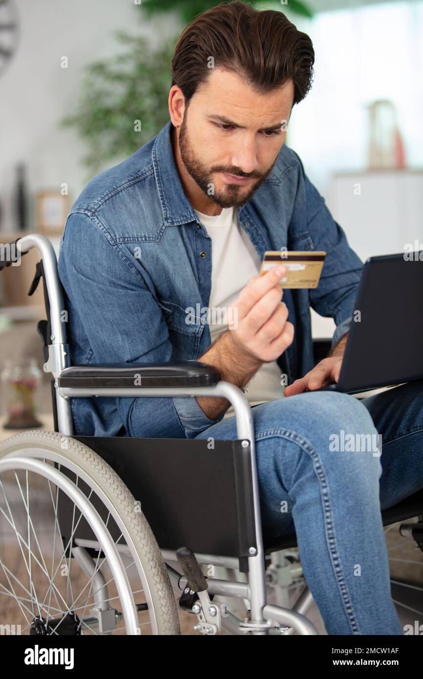 disabled man in wheelchair making online purchase on laptop Stock Photo ...