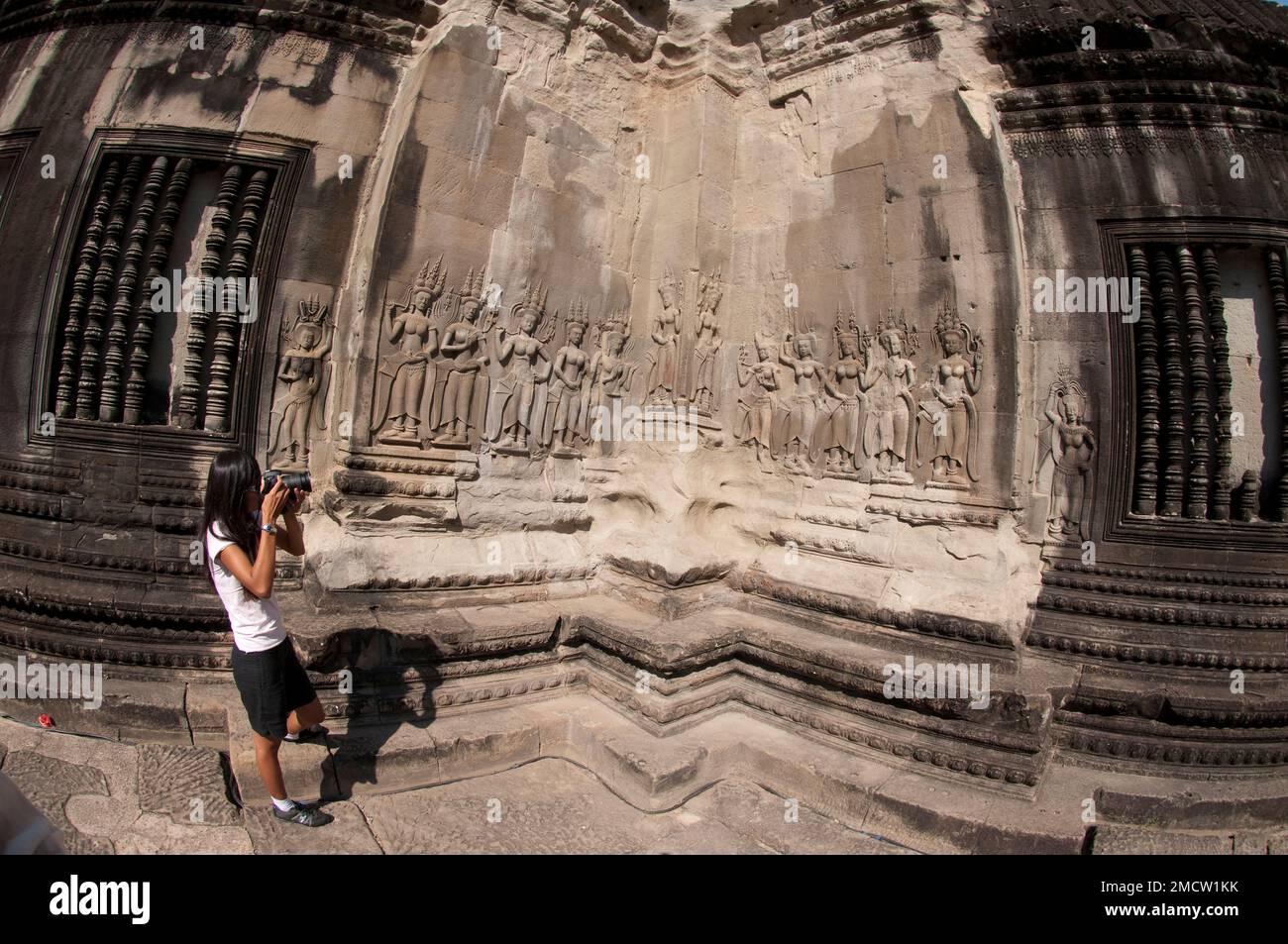 Woman photographling carvings of Apsaras, Angkor Wat temple, Siem Riep ...
