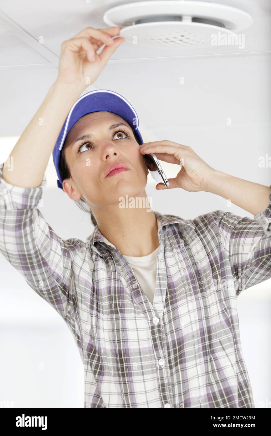 female worker on cell phone fixing a ceiling issue Stock Photo - Alamy