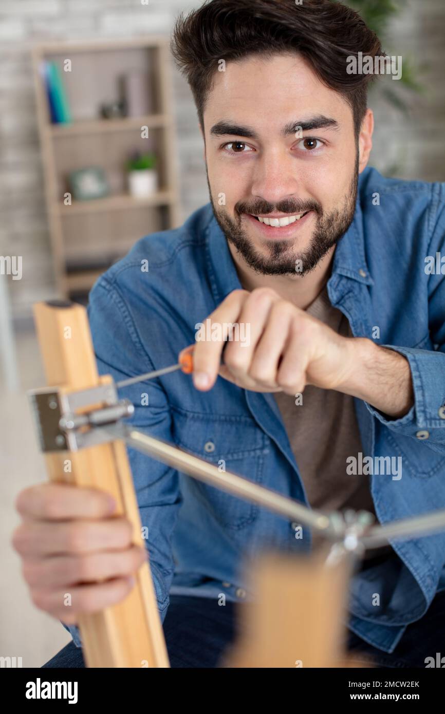 man putting together self assembly furniture in new home Stock Photo ...