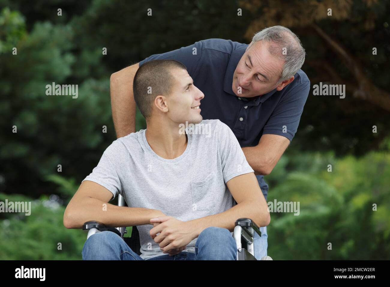 dad walking with disabled son in wheelchair at park Stock Photo - Alamy