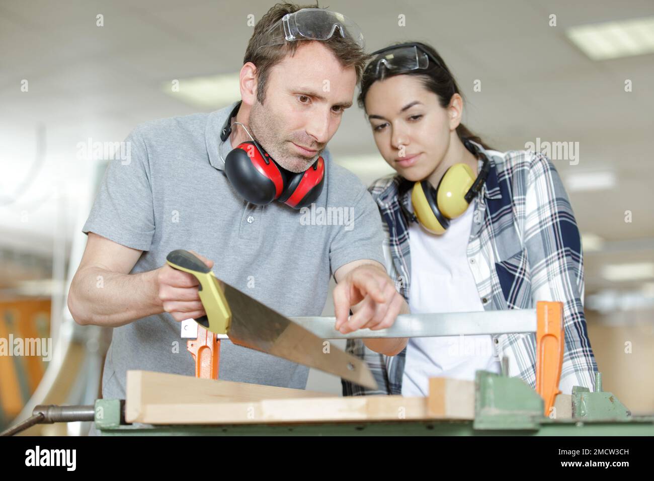 carpenter and apprentice working together in wood workshop Stock Photo ...
