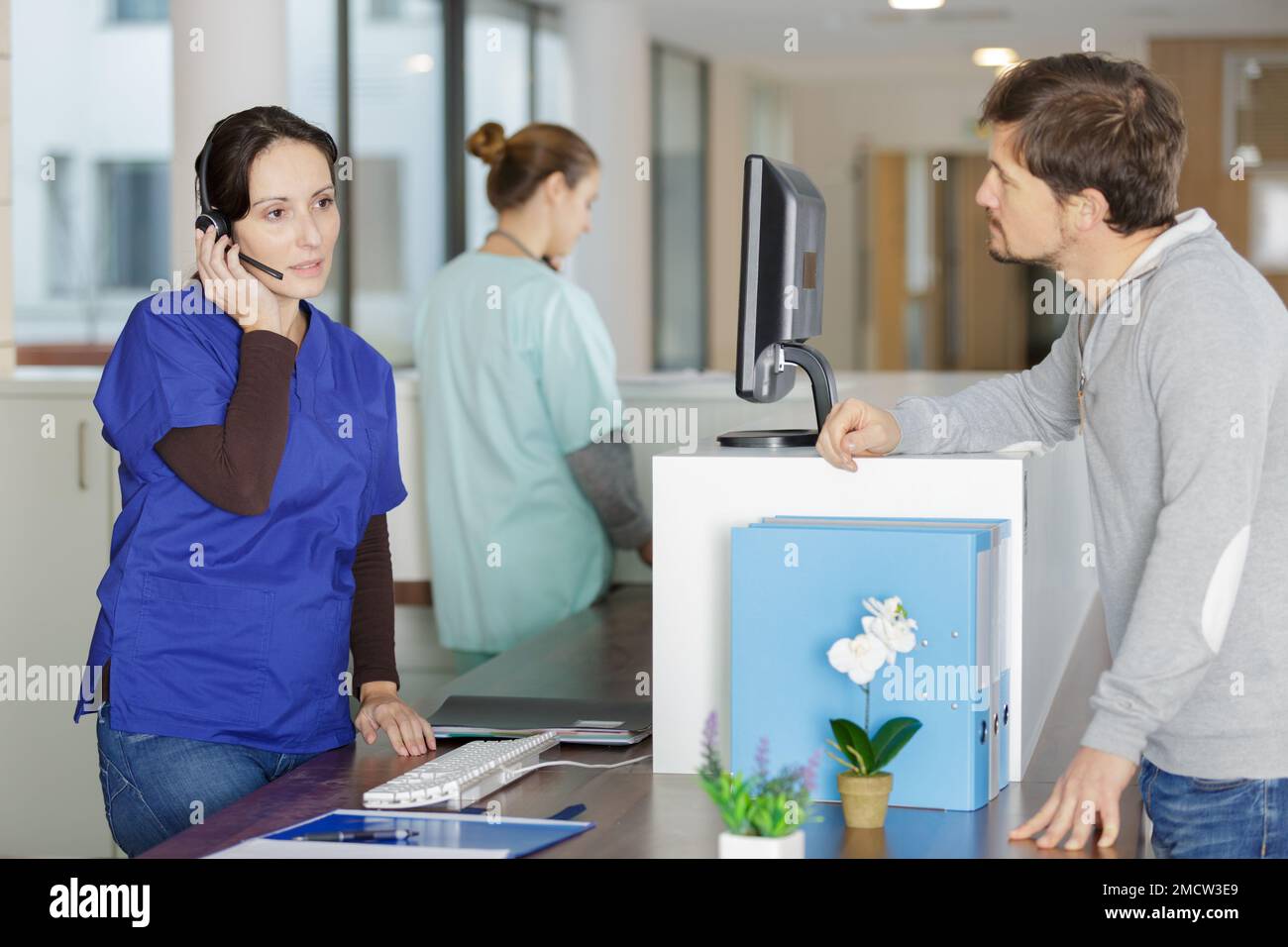 male patient with nurse at reception desk in hospital Stock Photo - Alamy