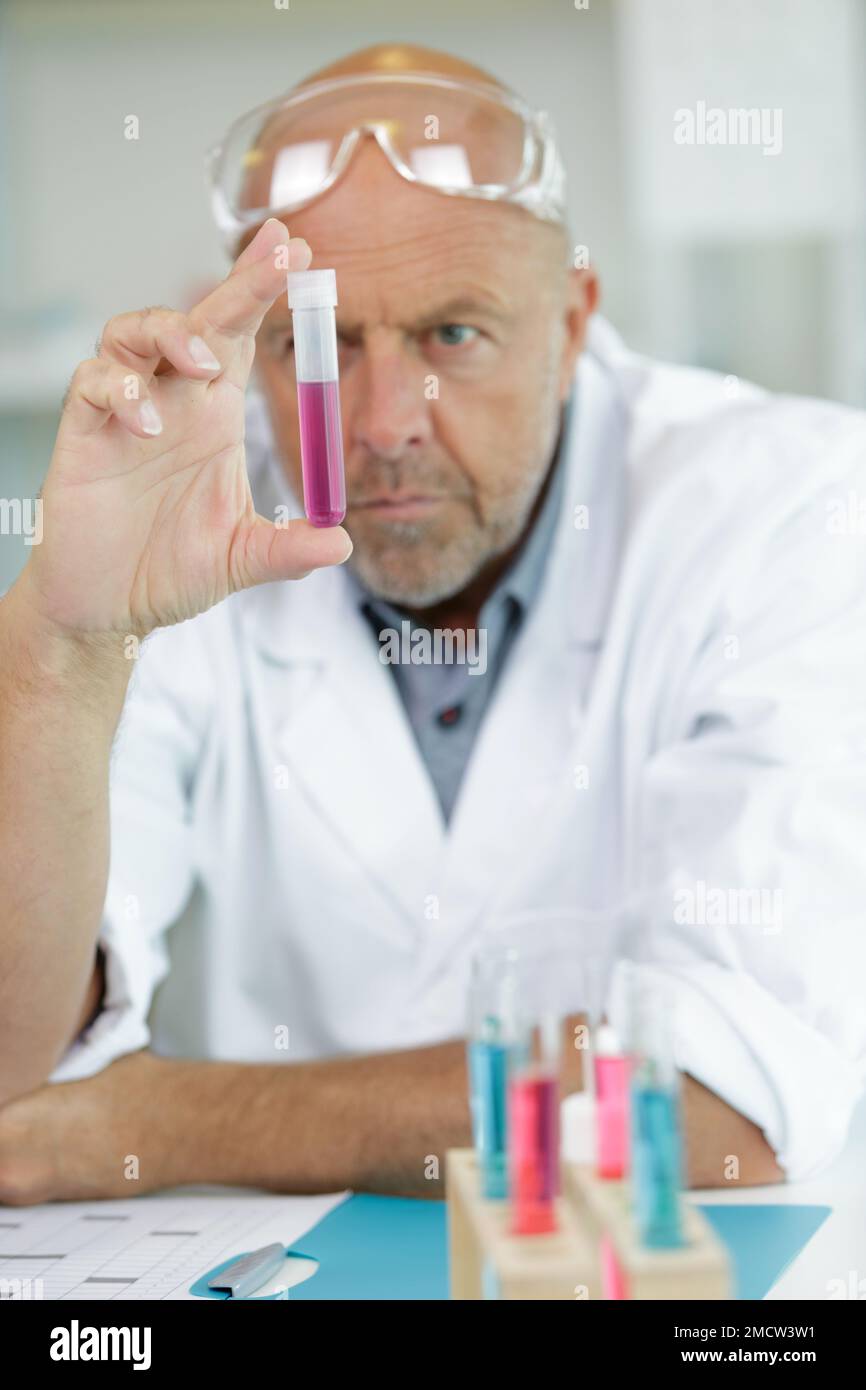mature worker looking at test tube Stock Photo - Alamy