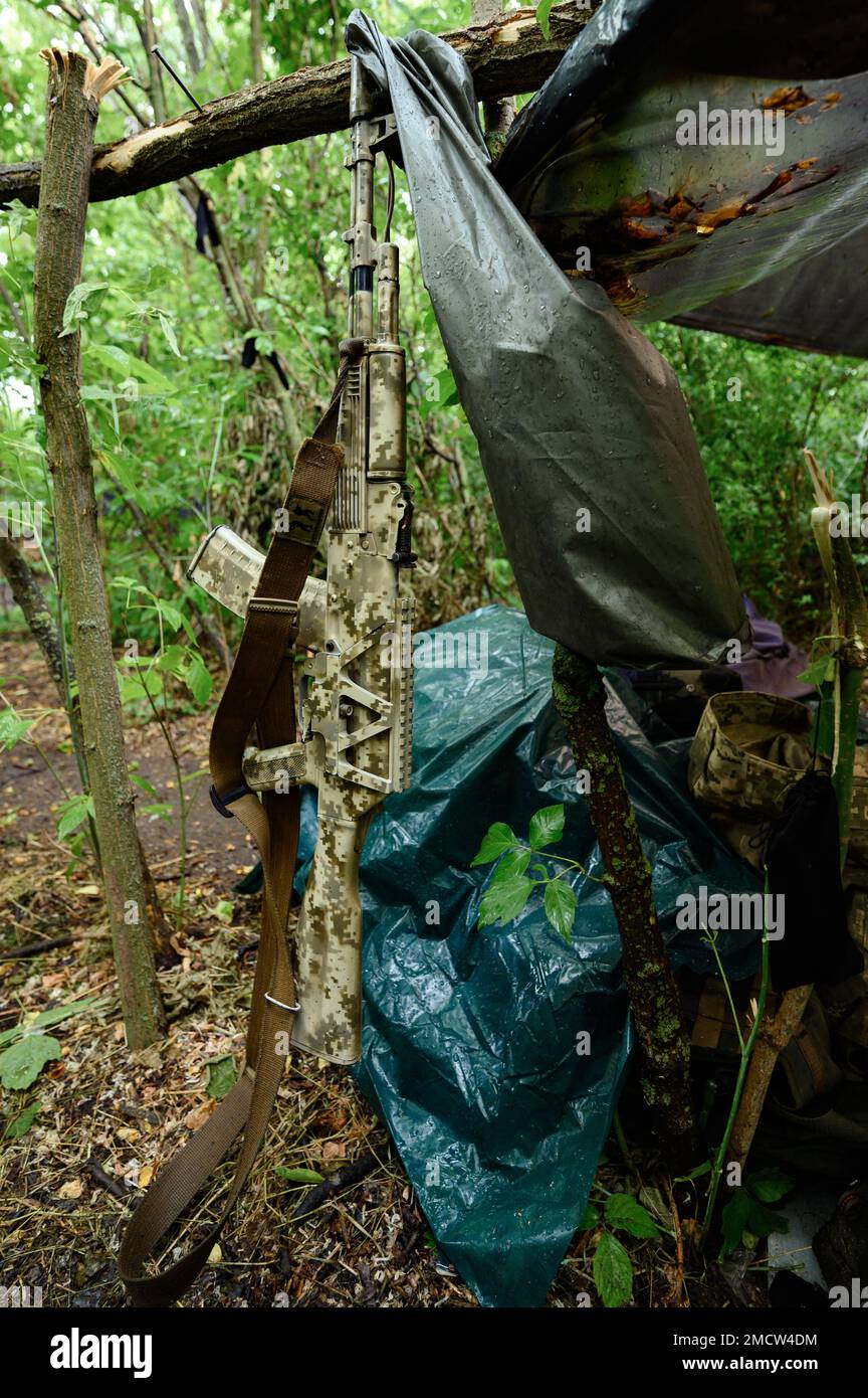 An automatic rifle near a tent in the forest, a military tent in the ...