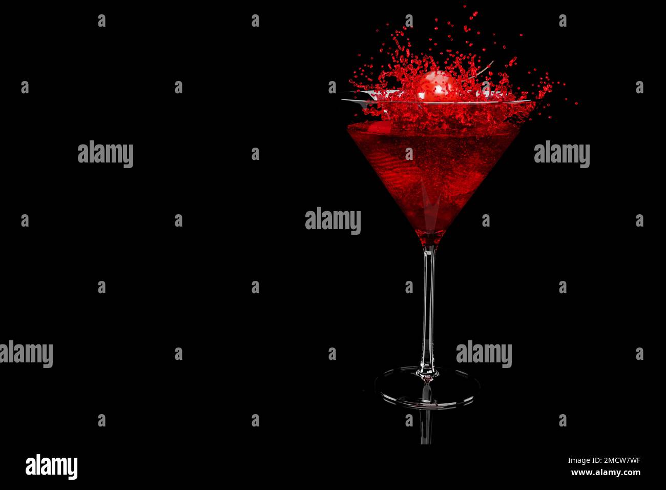 Cherry falling into splashing cocktail in martini glass isolated on ...