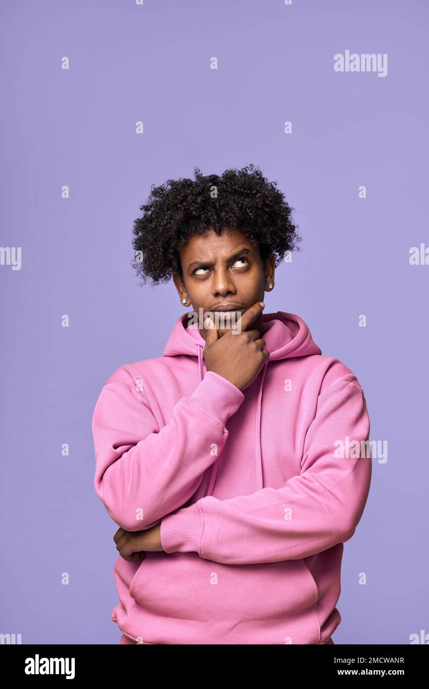 Thoughtful confused African teen guy thinking isolated on purple ...
