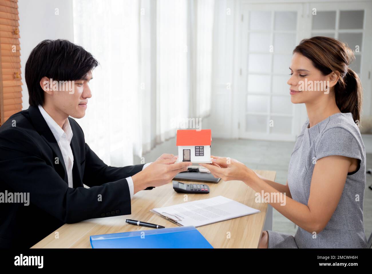Young realtor man real estate giving house model to hands customer ...