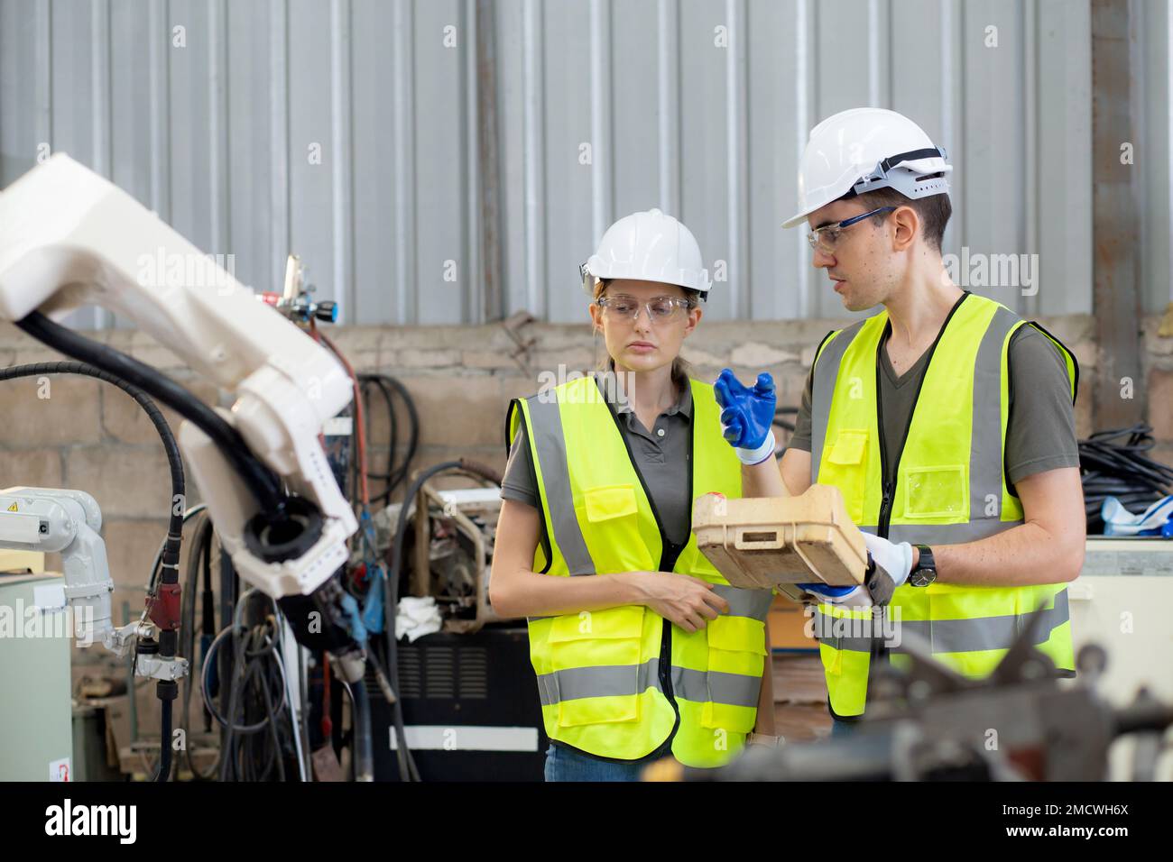 Engineer man and woman talking and explaining about robot arms ...