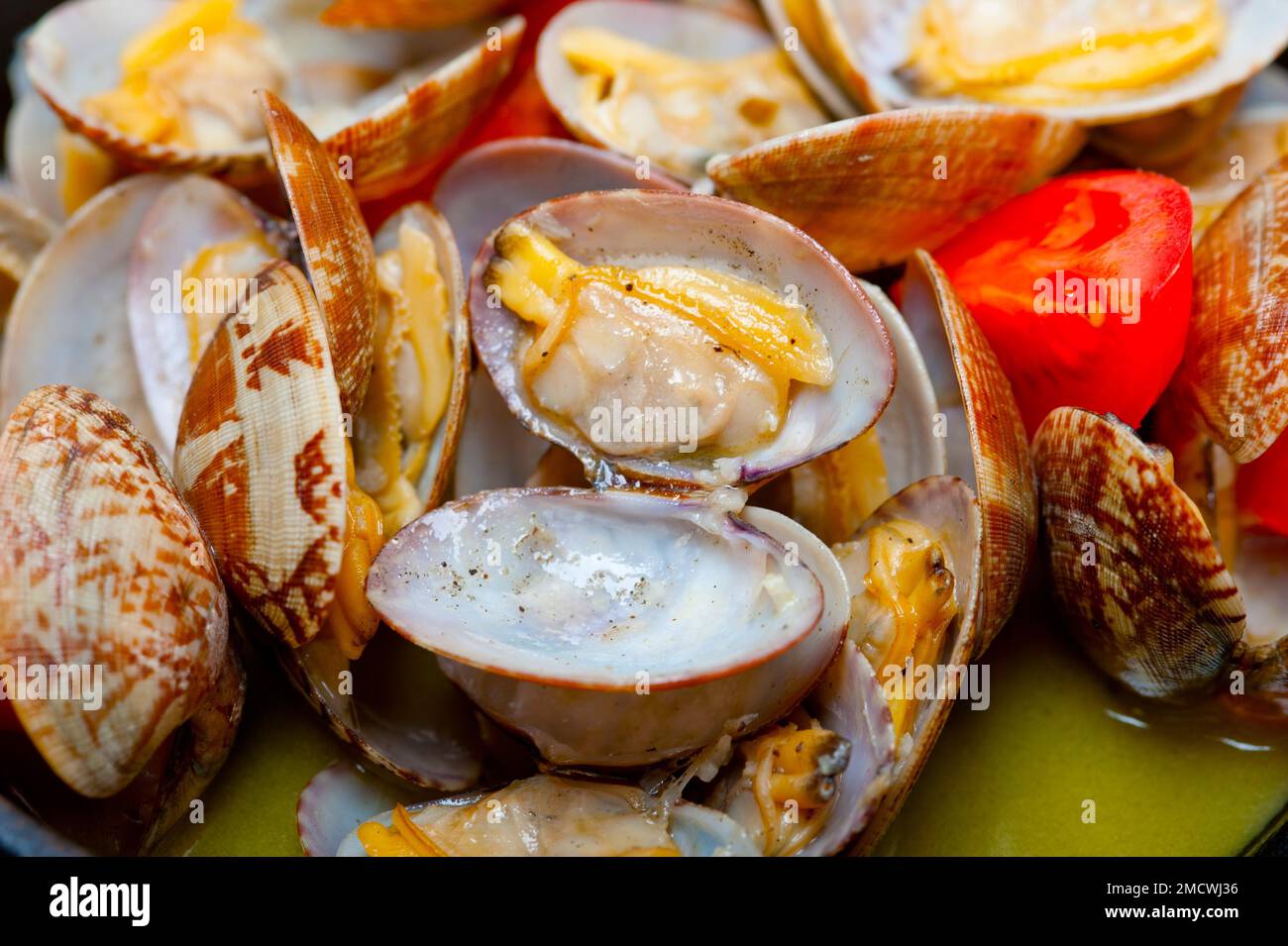 Fresh clams stewed on an iron skillet over wite rustic wood table Stock ...