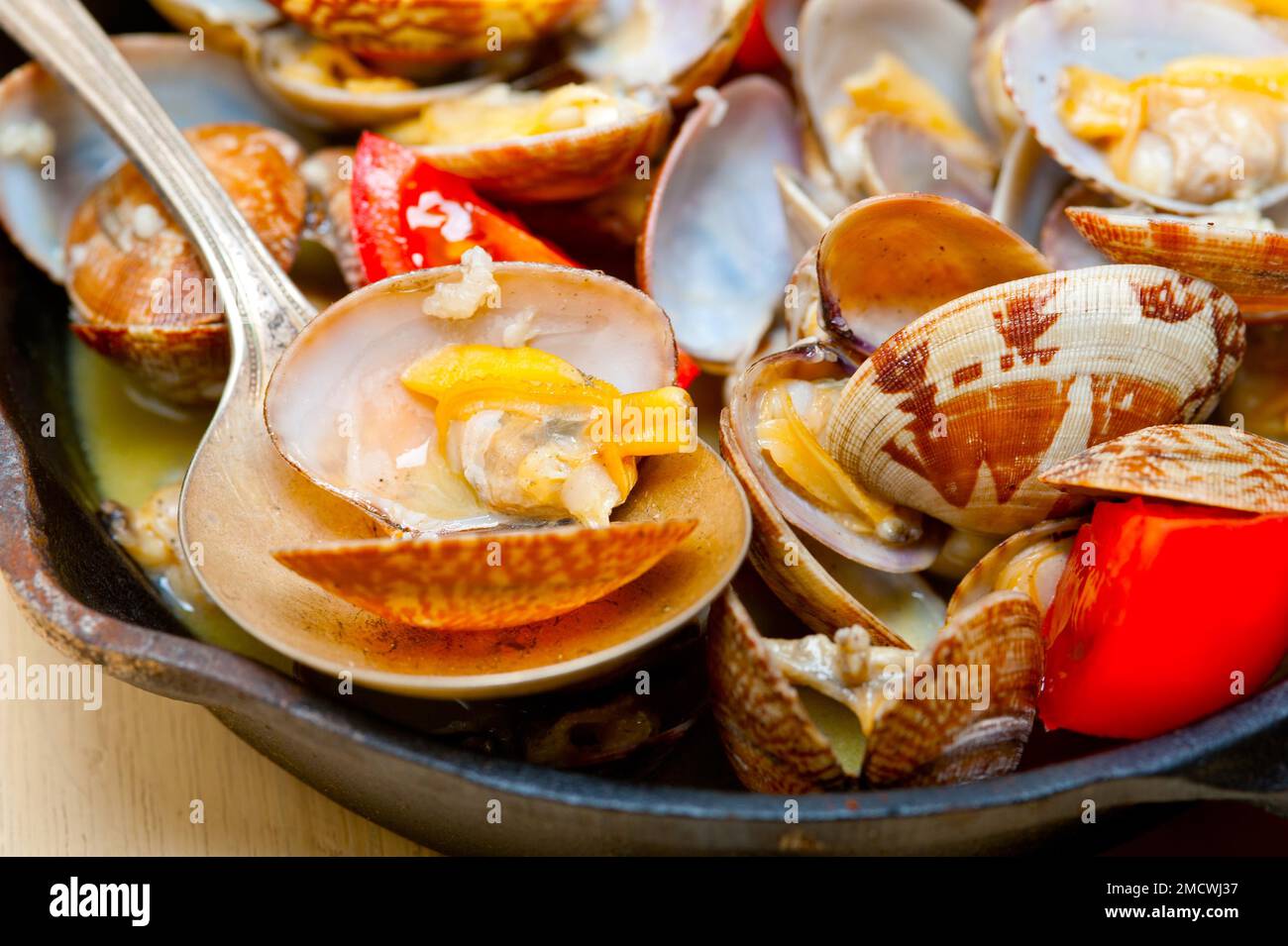 Fresh clams stewed on an iron skillet over wite rustic wood table Stock ...