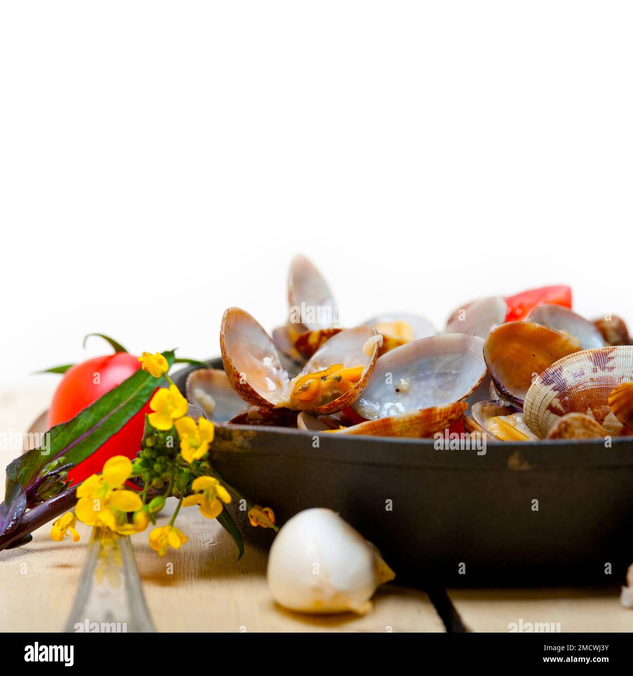 Fresh clams stewed on an iron skillet over wite rustic wood table Stock ...