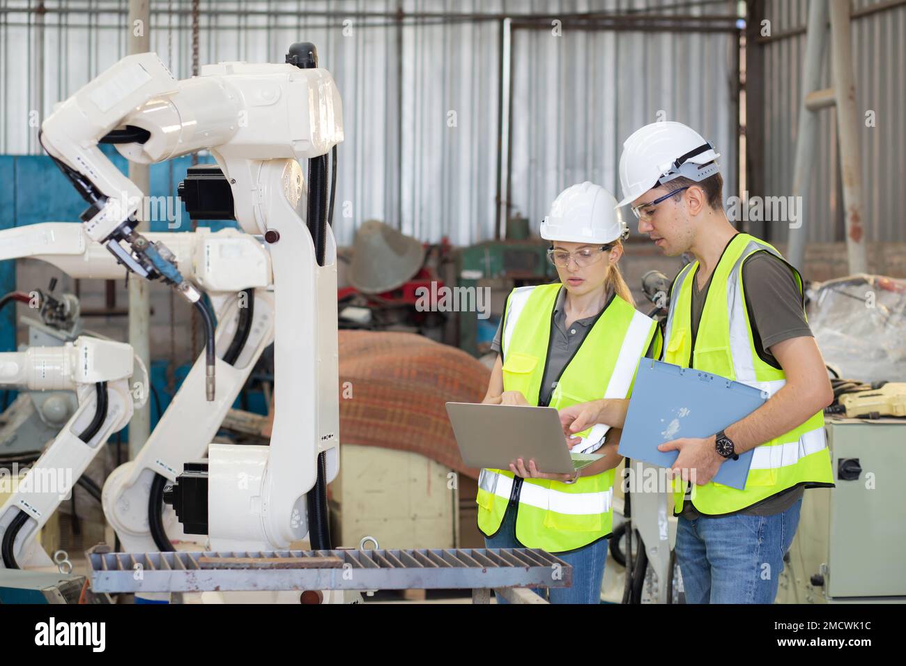 Engineer man and woman talking and explaining about robot arms ...