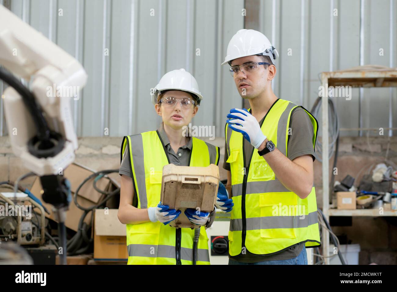 Engineer man and woman talking and explaining about robot arms ...