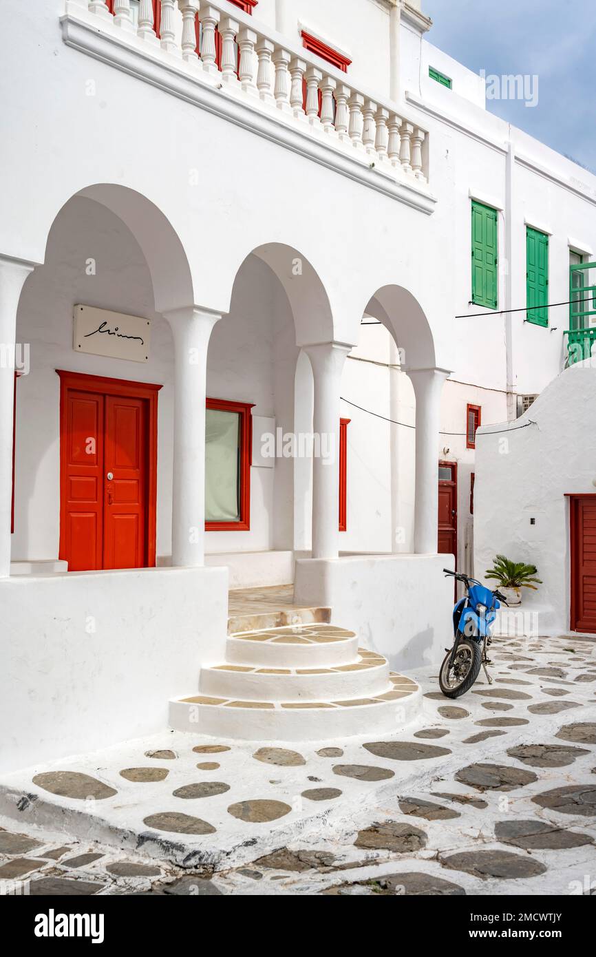 White Cycladic house with columns and red door, alleys of the old town ...