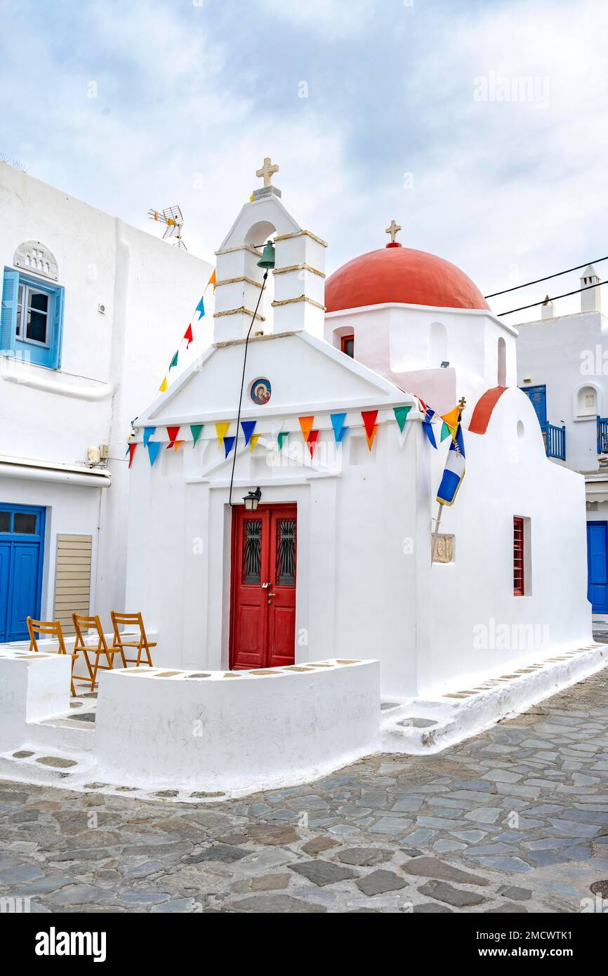 White Cycladic Greek Orthodox Church decorated with flags, alleys of ...