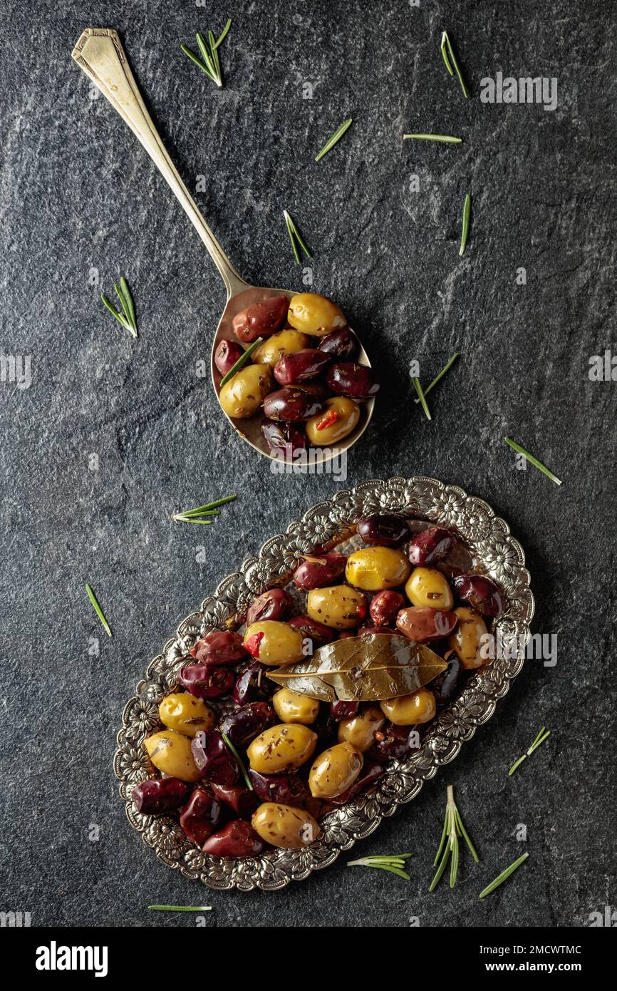 Spicy olives on a black stone table. Top view Stock Photo - Alamy