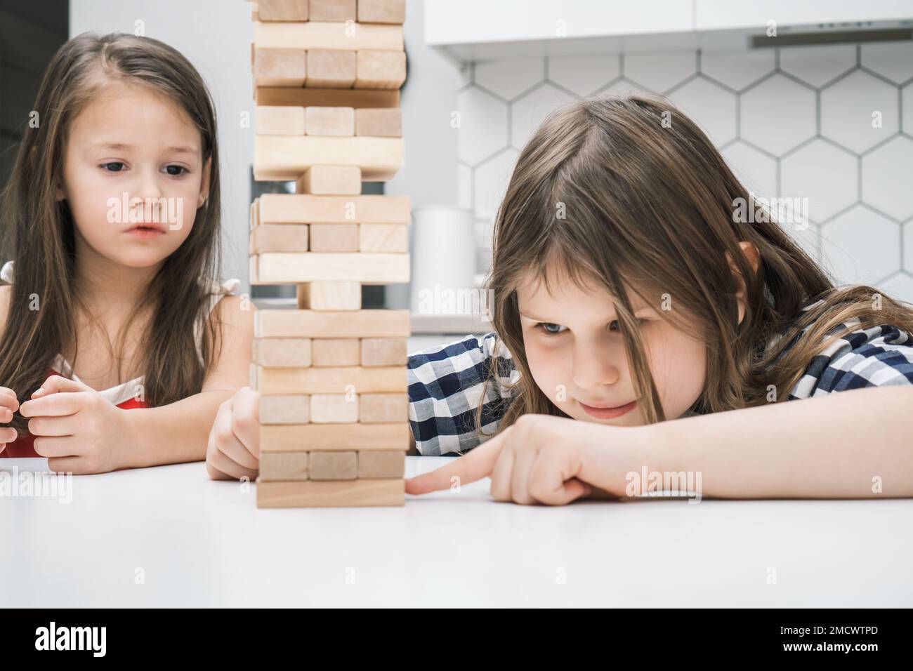 Two schoolgirls friends children playing board game Jenga on table in ...