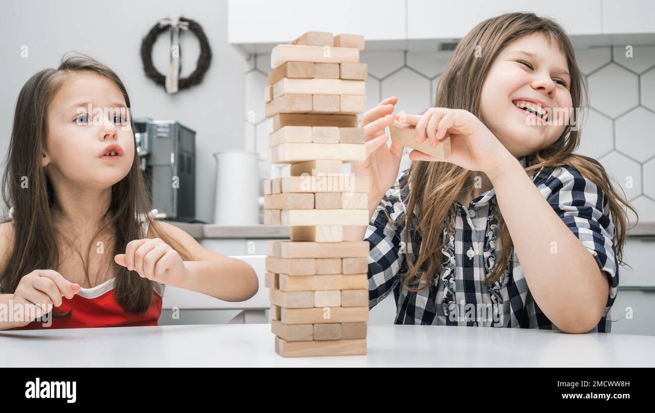Two preteen girls friends children playing board game Jenga on table in ...