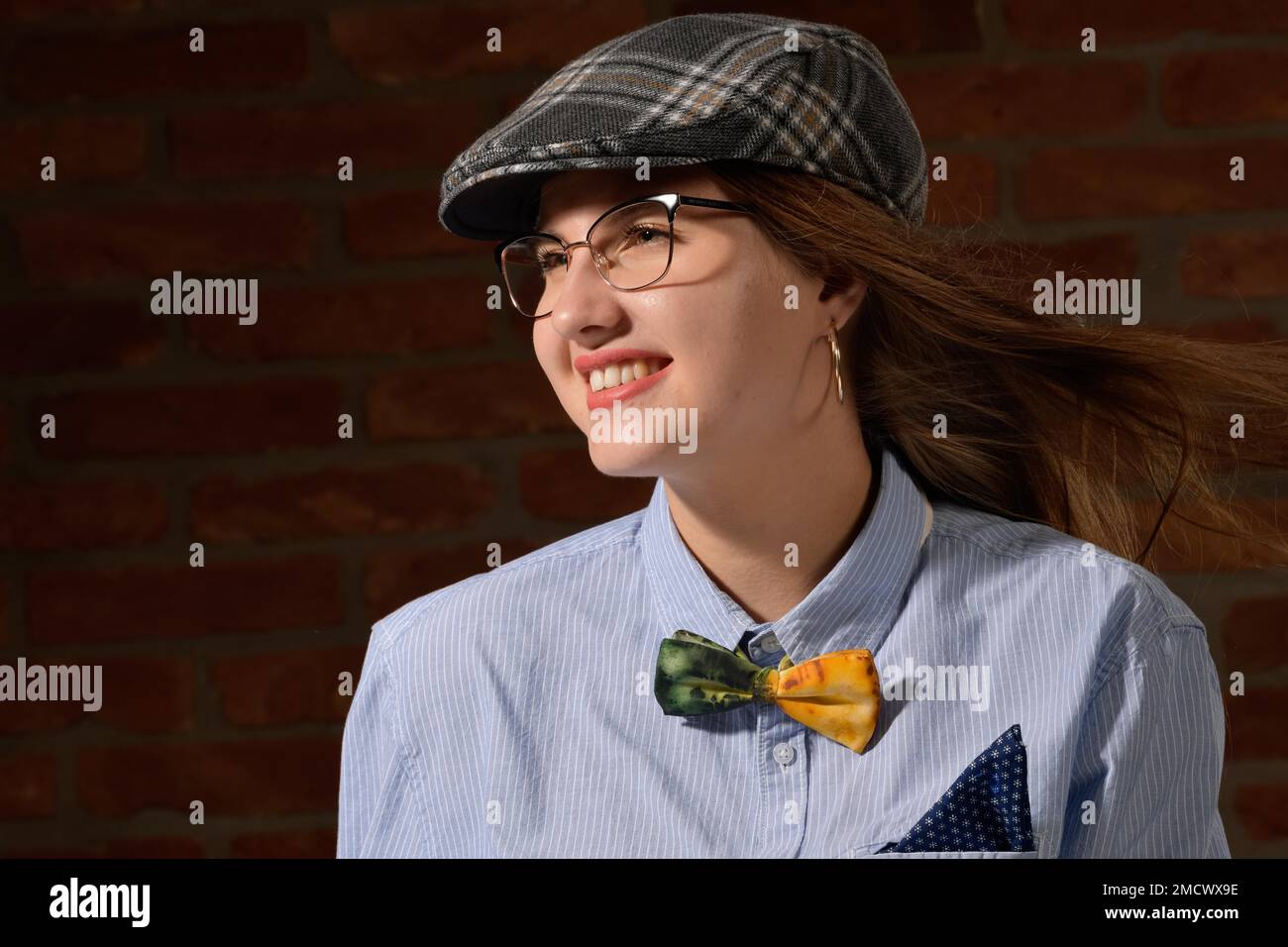 Pretty very young woman with long brunette hair wears a blue shirt with ...