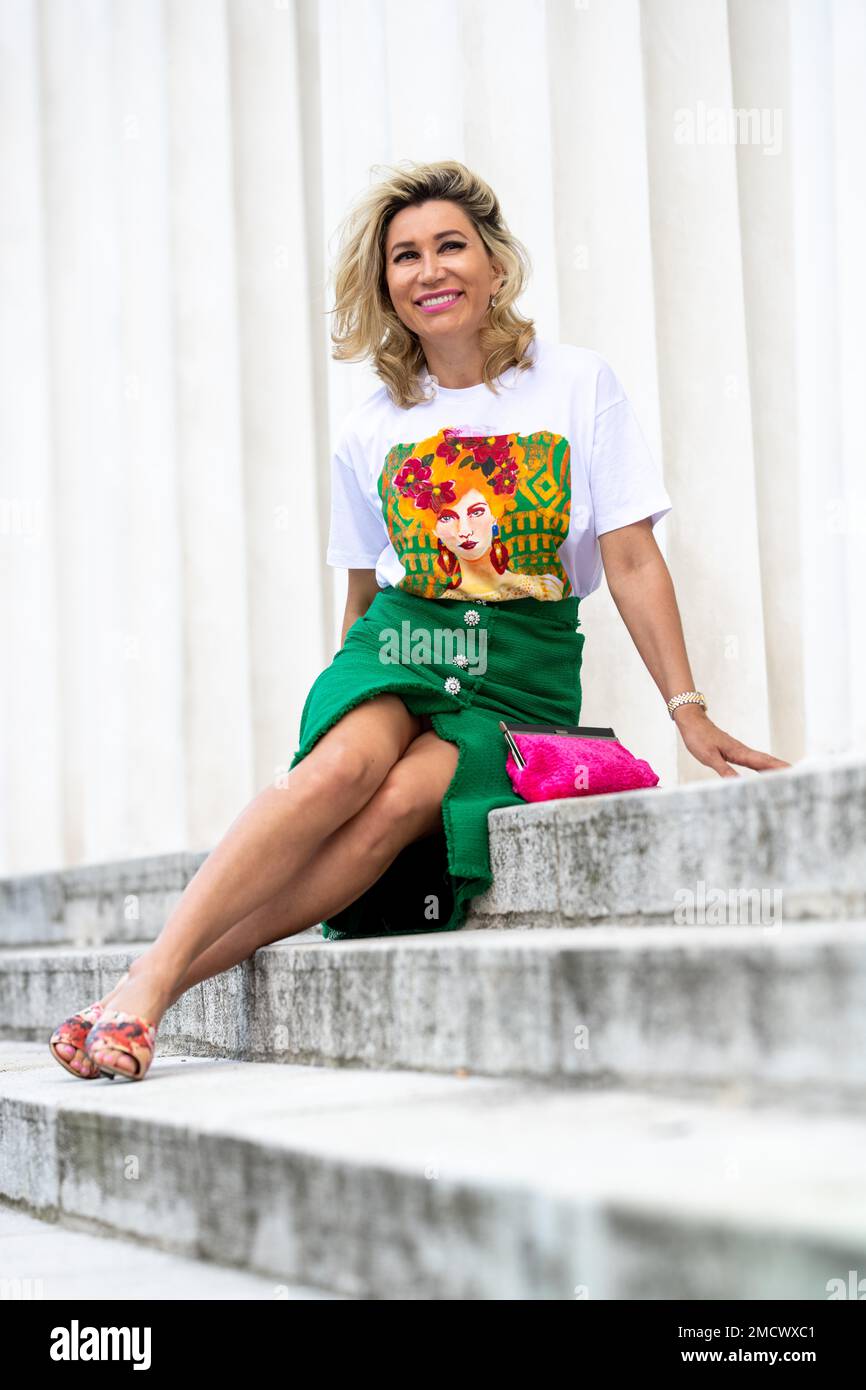 Pretty woman in her prime with long curly blond hair sits on a ...